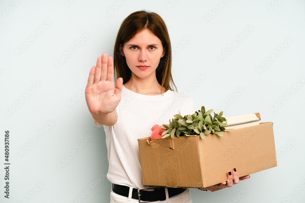Young English woman making a move while picking up a box full of things ...