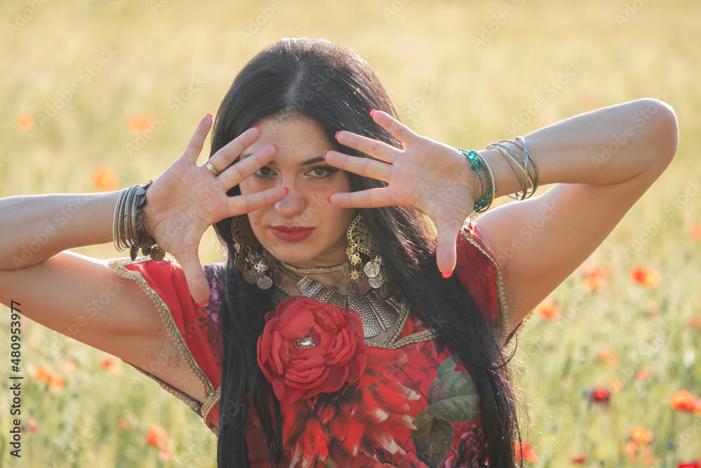 Gypsy girl in a field of poppies. Red gypsy dress. Beautiful brunette ...