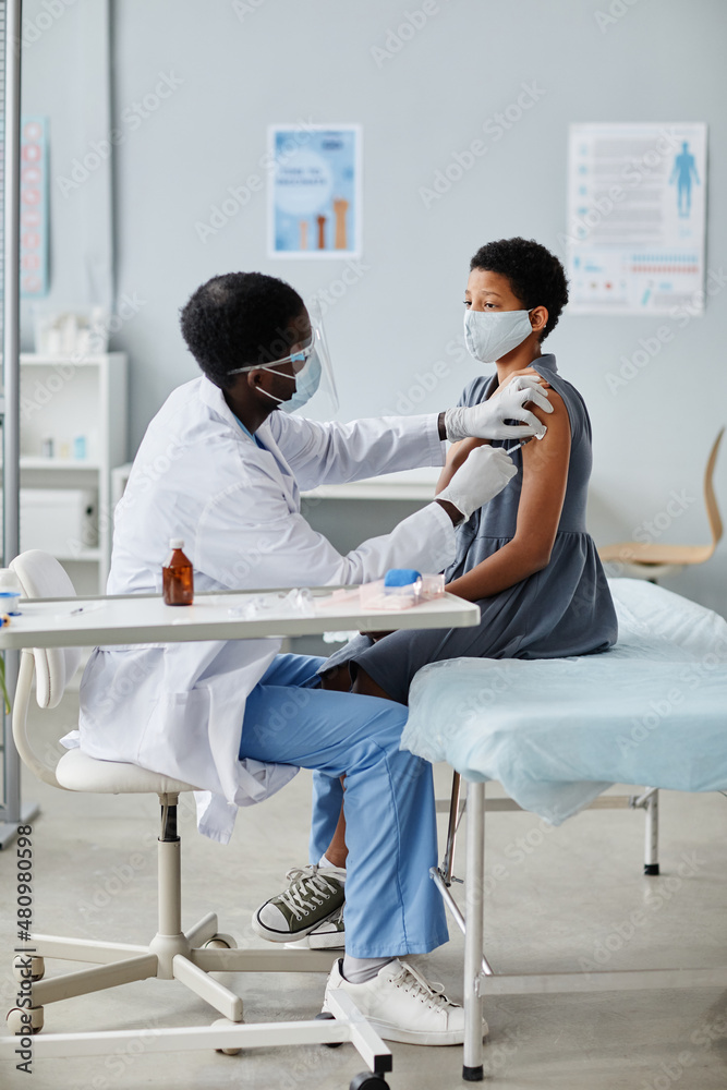 Vertical portrait of African-American girl getting vaccinated in child ...