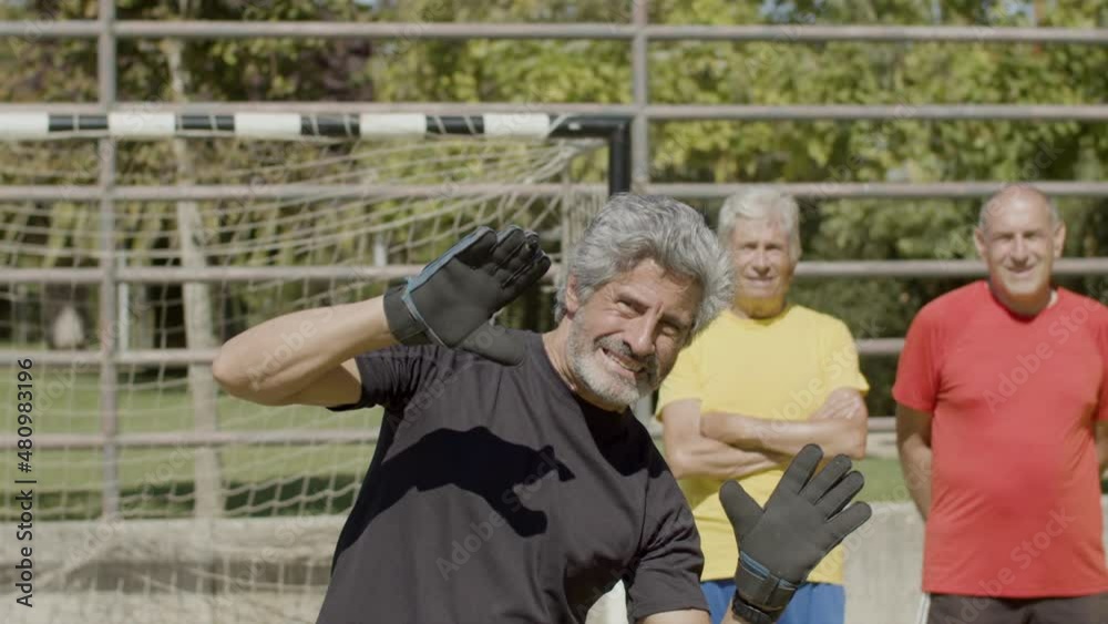 Senior goalkeeper standing in sports stadium, posing for camera. Front ...