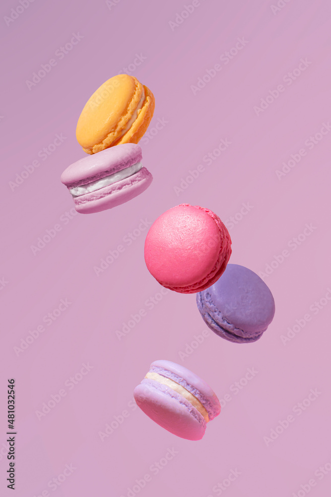 Multicolored macaron almond cakes take off on a purple background ...