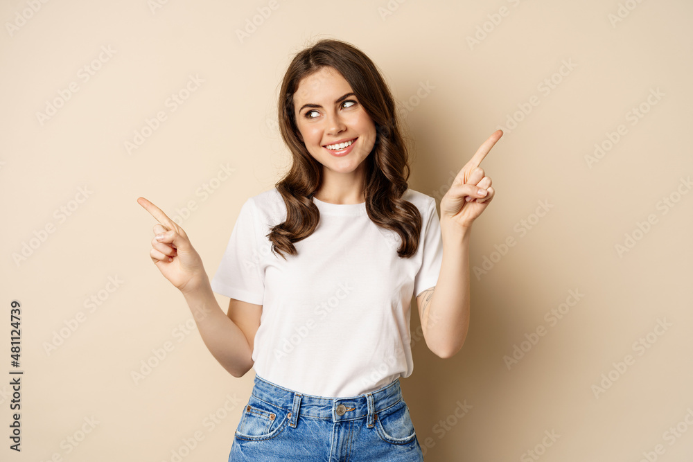 Happy authentic girl smiling, pointing fingers sideways, showing left ...