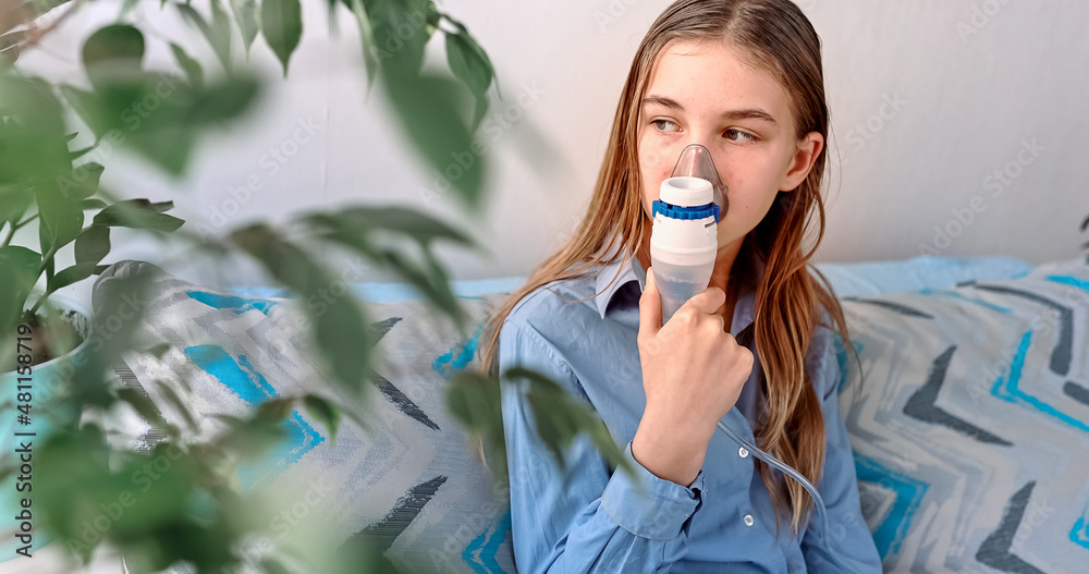Teenage girl makes inhalation with a nebulizer equipment. Sick child ...