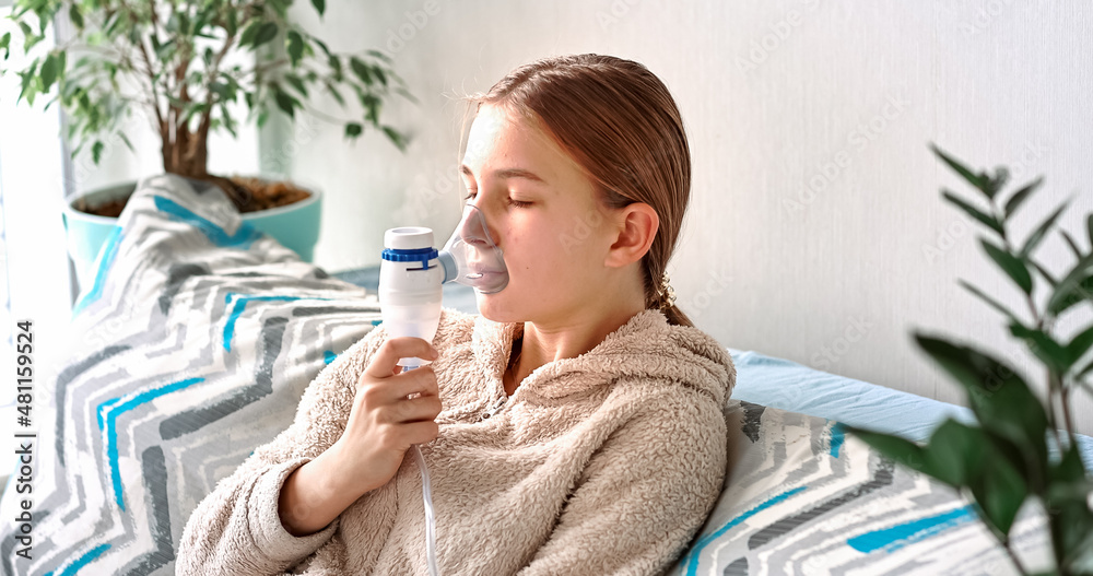 Teenage girl makes inhalation with a nebulizer equipment. Sick child ...