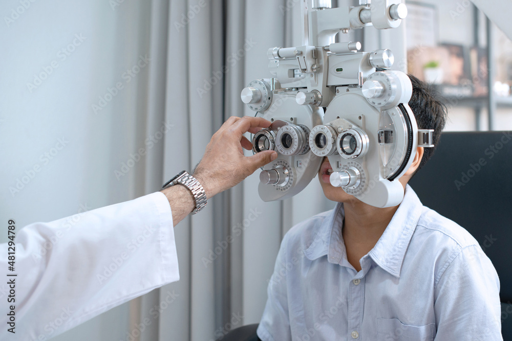 Indian boy looking through optical Phoropter during eye exam, The ...