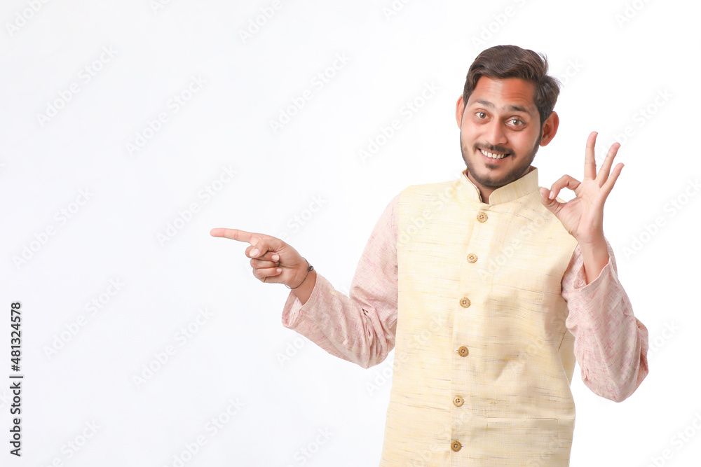 young indian man in traditional wear and showing direction on white ...