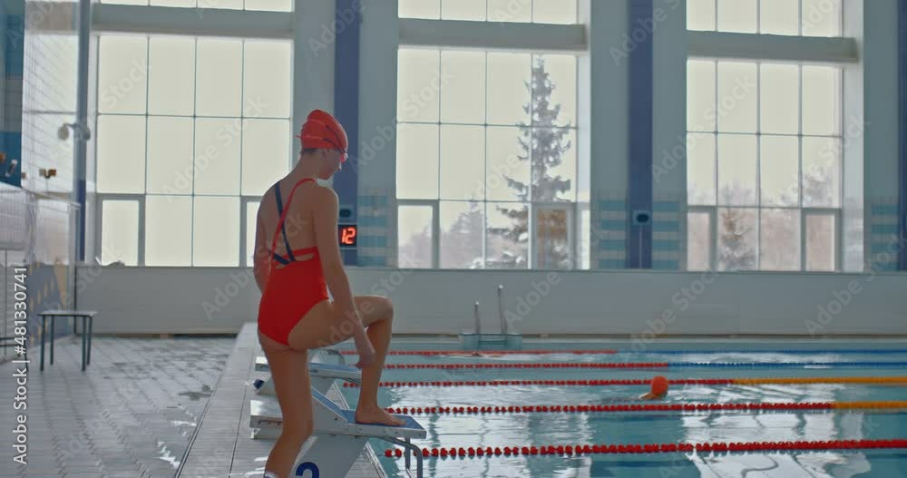 Swimming champion stands on the diving stand and prepares to dive into ...