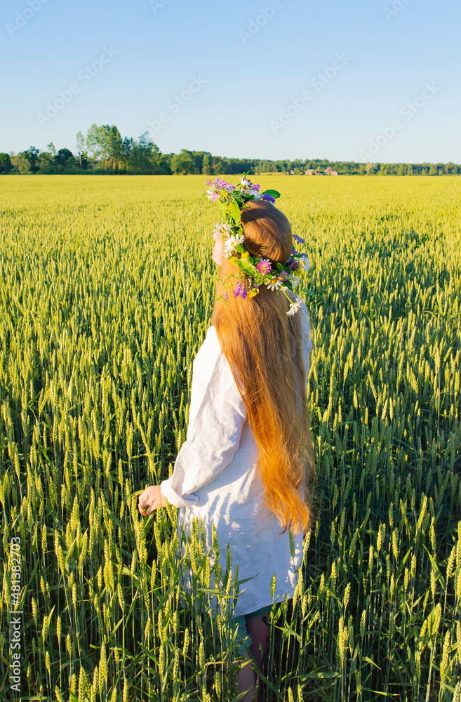 Long haired girl dreesed in white with the frower wreath on the head ...
