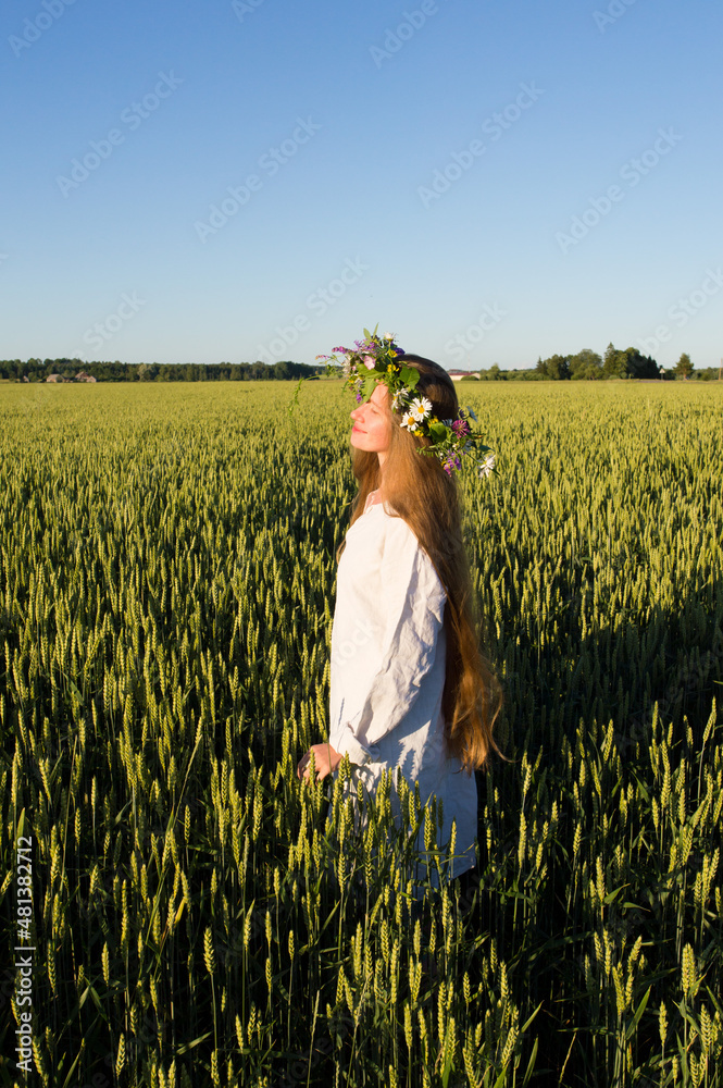 Long haired girl dreesed in white with the frower wreath on the head ...