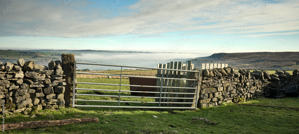 Let into a drystone wall, a 7 barred farm gate gives access to moorland ...