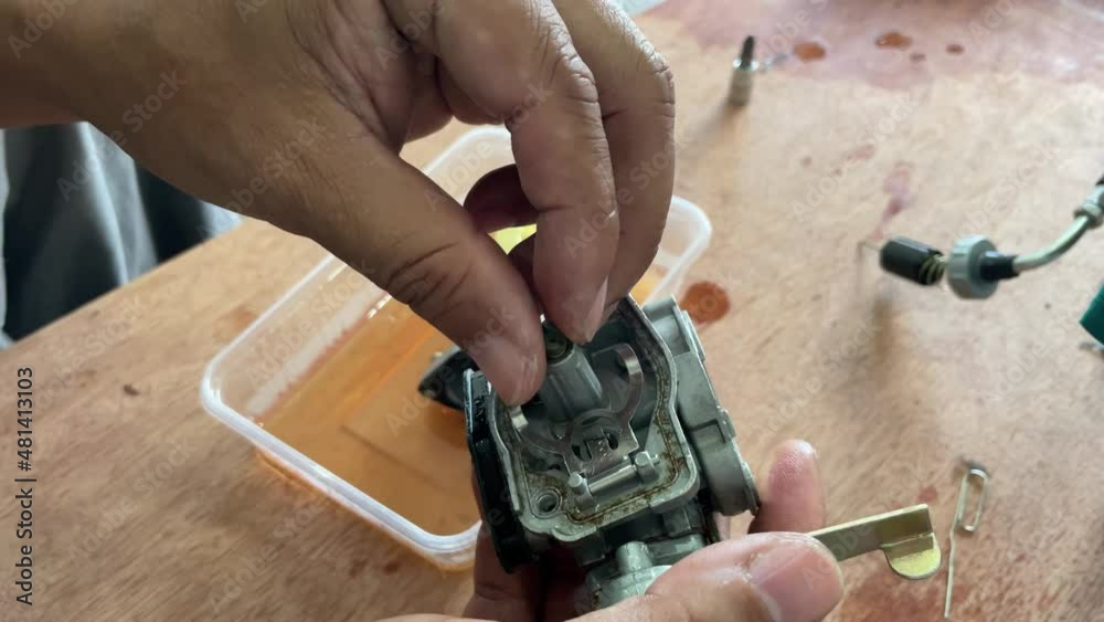 A young man is repairing a small two-stroke engine used for farming ...