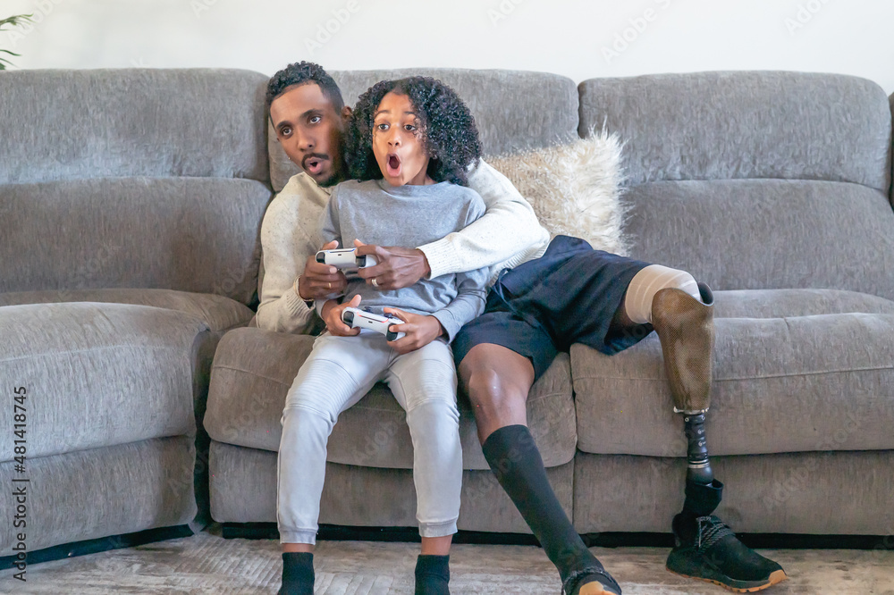 Boy playing video game with father with prosthetic leg Stock Photo ...
