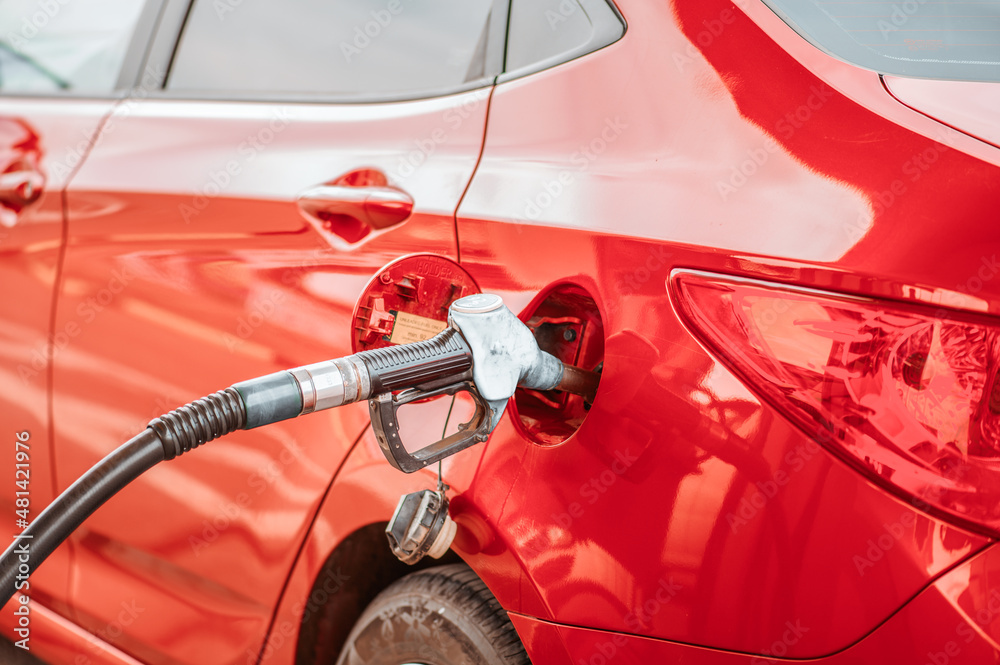 Refueling gun in the gas tank of a bright red car Stock Photo | Adobe Stock