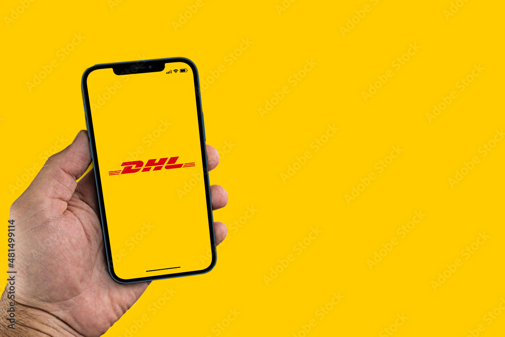 Male hand holding a smartphone with DHL International package delivery ...