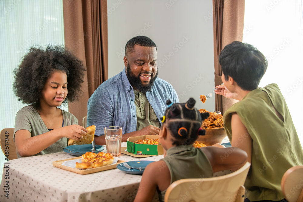 African family parents and two little daughter eating fried chicken and ...