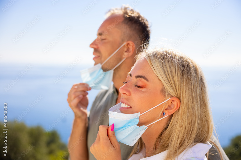 Woman and man taking of their facial masks and breathing fresh air ...