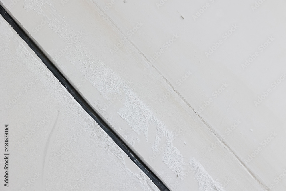 electrical cable is laid in groove in wall. electrical wires are ...