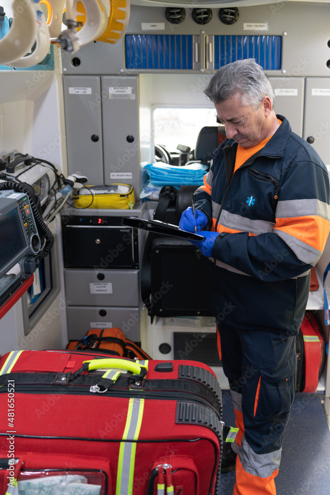 vertical photo of a middle-aged paramedic with gray hair making a check ...
