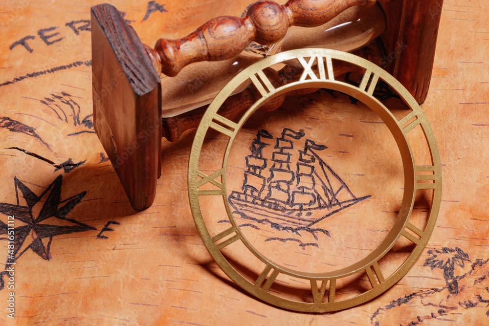 An hourglass and clock face lying on the order of antique nautical ...