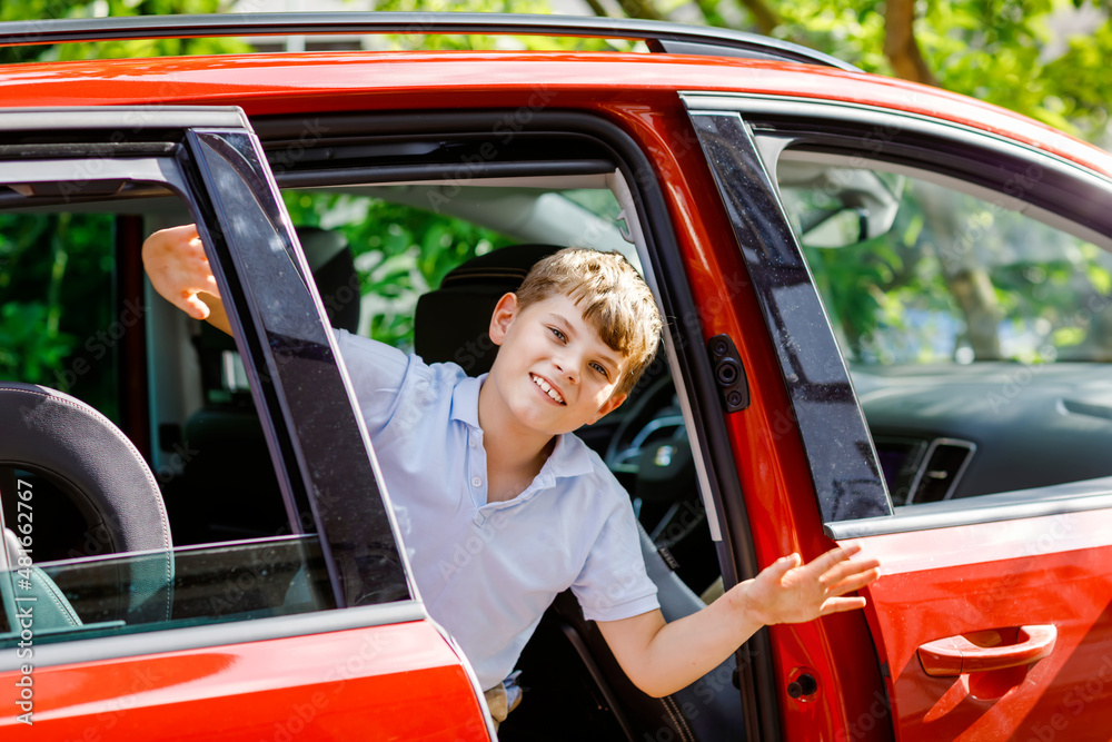 Happy child, school boy sitting in car before leaving for summer ...