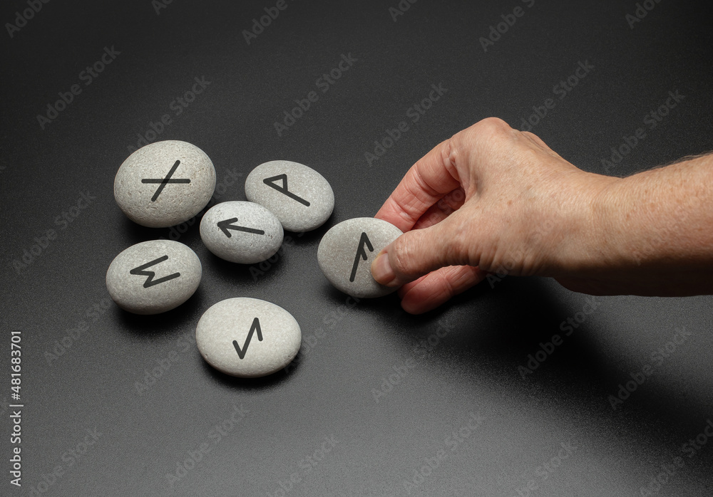 Fortune telling with symbols on stone. Hand holding norse rune stones ...