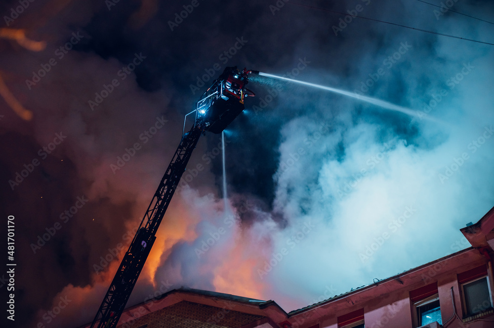 Firefighter on pull-out crane put out a fire in a burning building ...