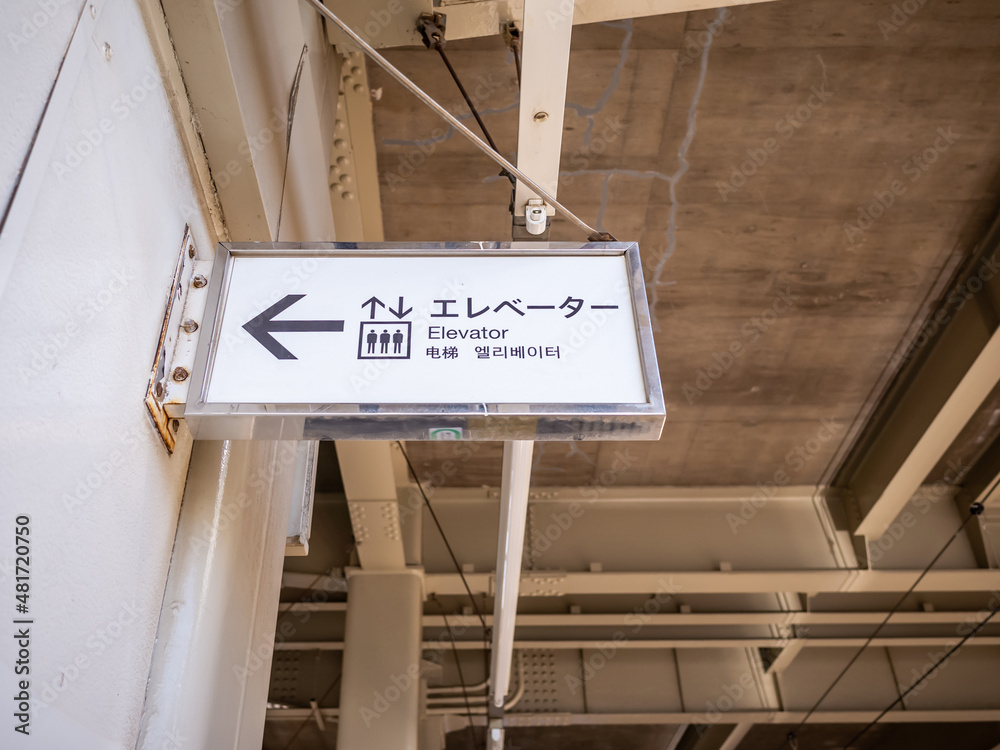 white signboard on the wall indicating the direction to the elevator ...