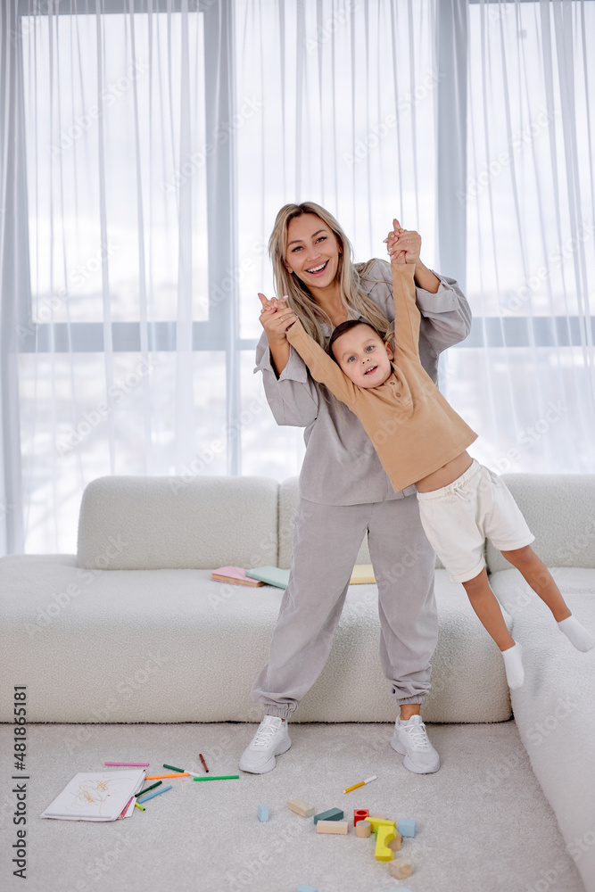 Cheerful mother have fun with son in cozy light living room, raising ...