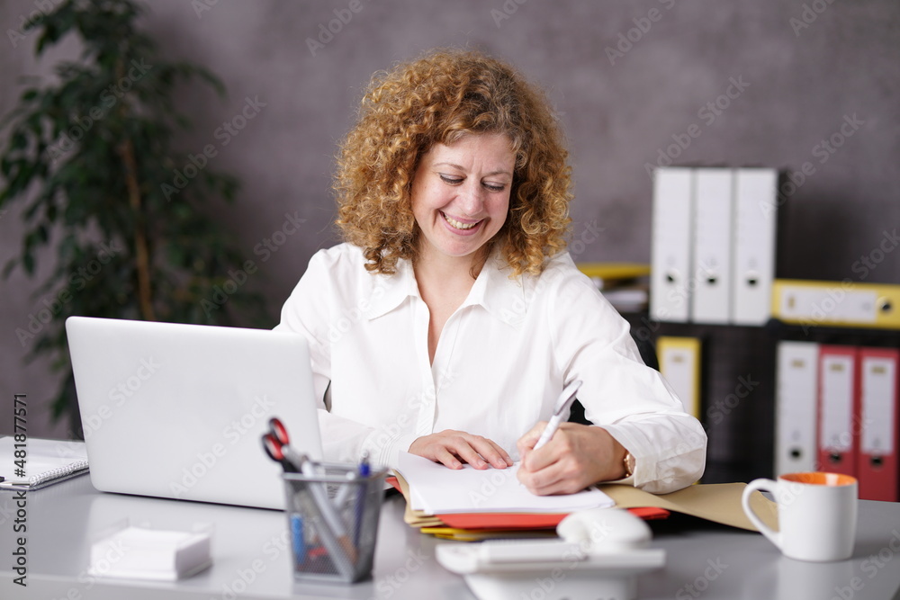 Sekretärin sitzt am Schreibtisch und schreibt in Akte Stock Photo ...
