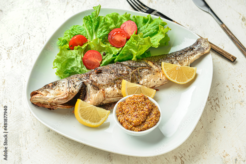 Plate with delicious sea bass fish, vegetables, bowl with mustard seeds ...