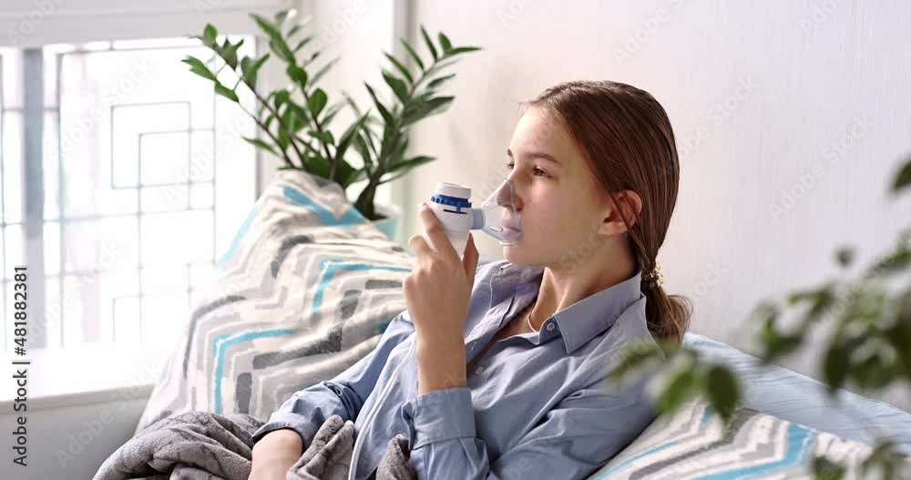 Teenage girl makes inhalation with a nebulizer equipment. Sick child ...