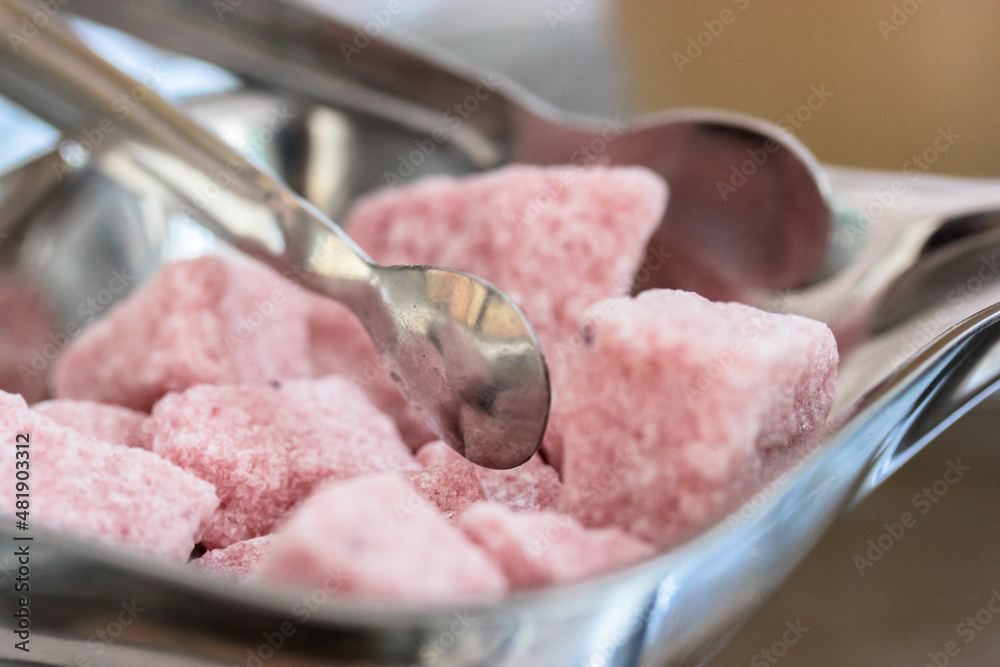 The pink unrefined lump sugar cubes and the metal sugar serving tongs ...