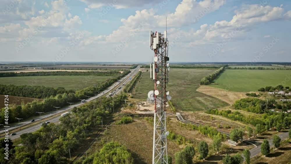 Telecommunication tower 5G near highway with car traffic. Telecom tower antenna and satellite ...