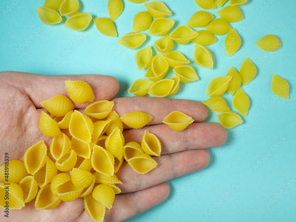 Shell-shaped pasta falls from your hand. Italian food. Cuisine of the ...