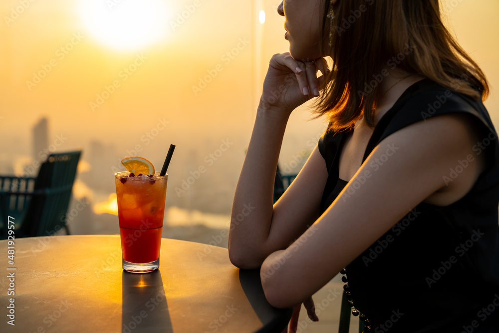 Asian woman drinking cocktail while waiting for meeting with friends at ...