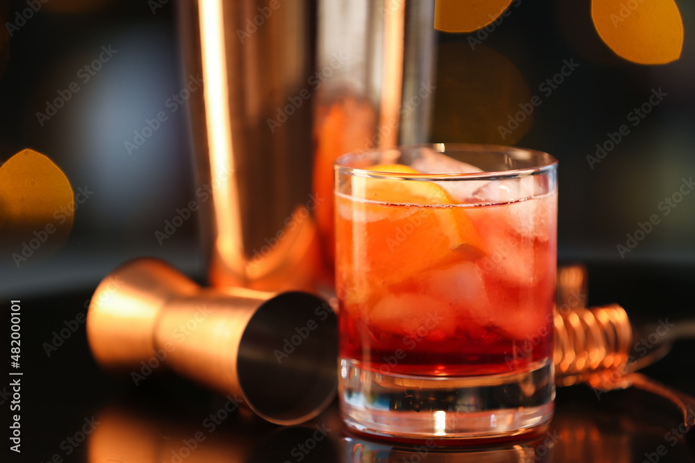Glass of tasty Negroni cocktail and measure cup on table against ...