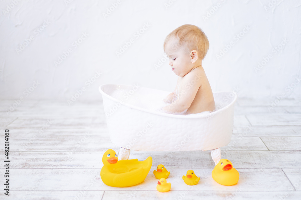 Foto de cute little baby girl bathing in a bathtub with foam and soap ...