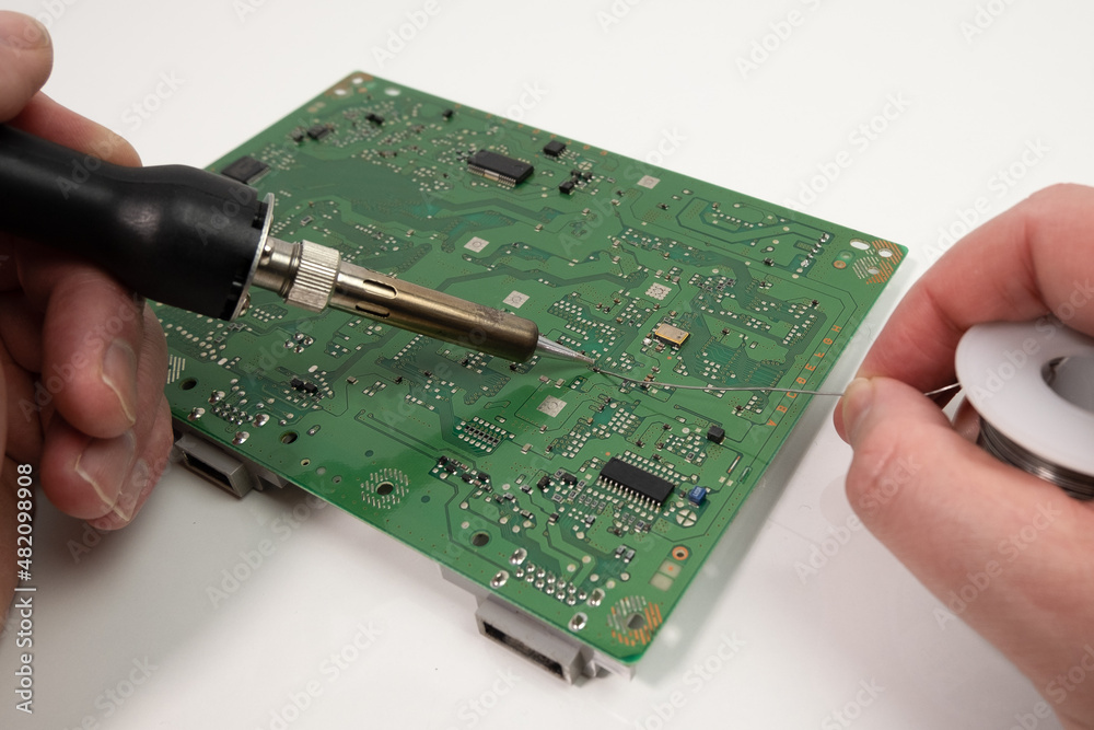 Technician repairing games console using soldering iron, soldering a ...