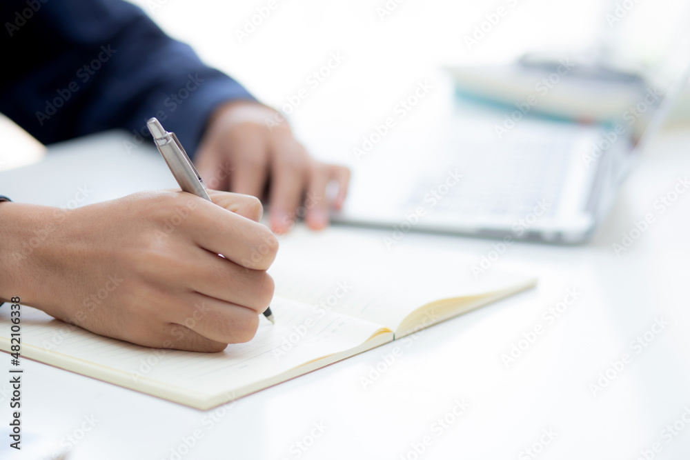 Closeup hand of man writing on notebook with pen on desk, freelance is ...