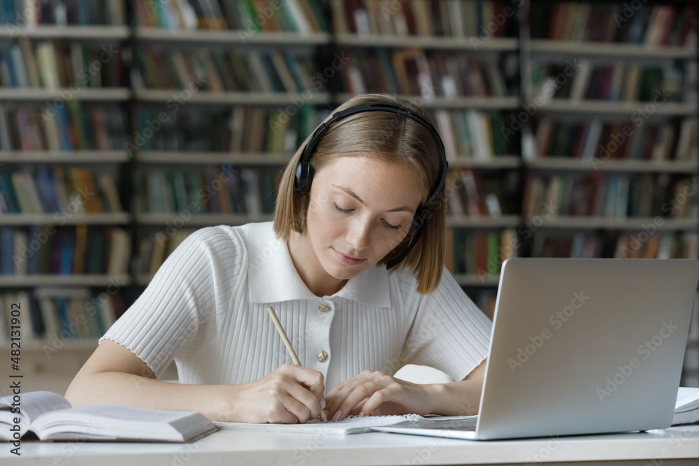 Serious hardworking student girl listening to audio tutorials from ...