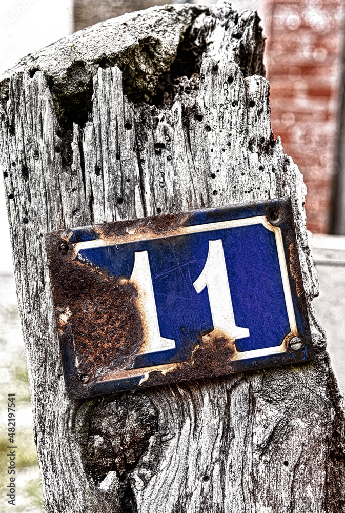 Chapa muy antigua y oxidada con el número once escrita atornillada en ...