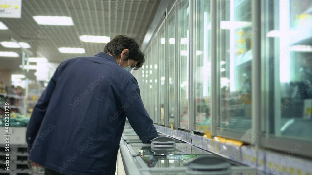Young male consumer doing shopping at frozen food section of ...