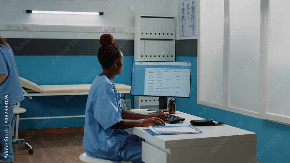 Medical assistant typing on computer keyboard in cabinet. Woman working ...