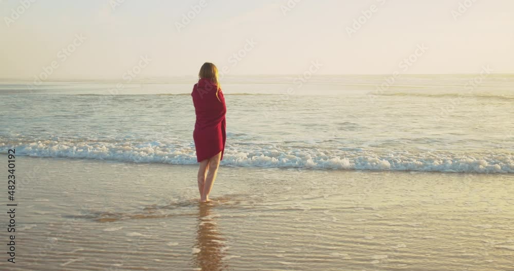 Rear view young girl wrapped in red towel on the beach. Caucasian woman ...