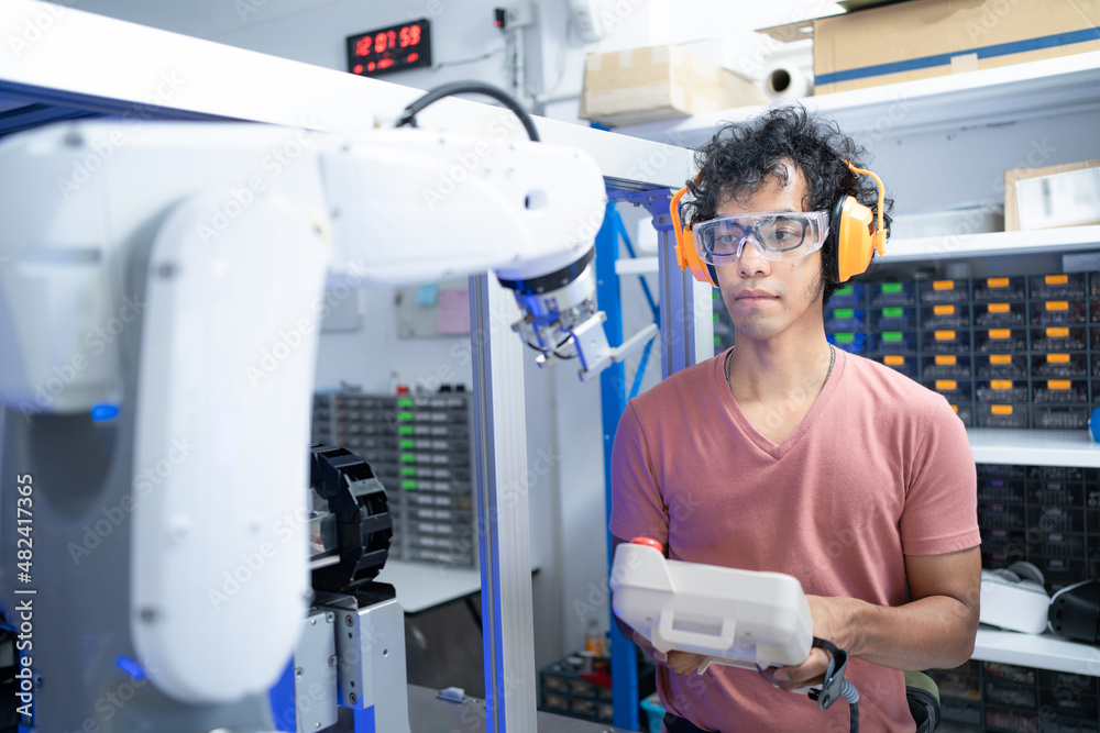 Caucasian male engineer with a curly hair in safety goggles and ear ...