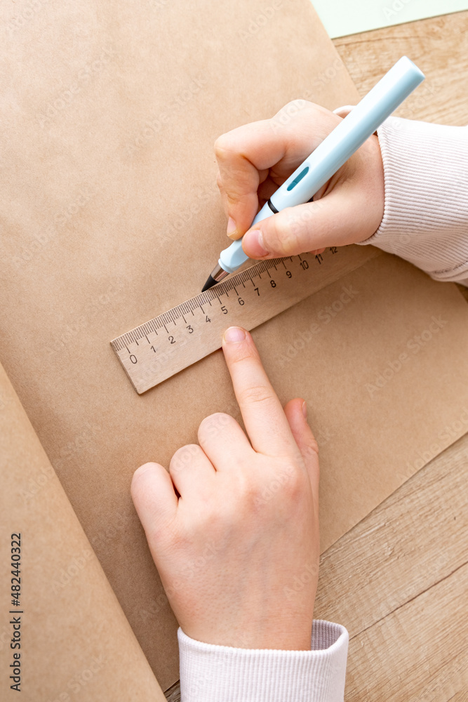 Close-up of child hands in process of sketching with pencil on craft ...