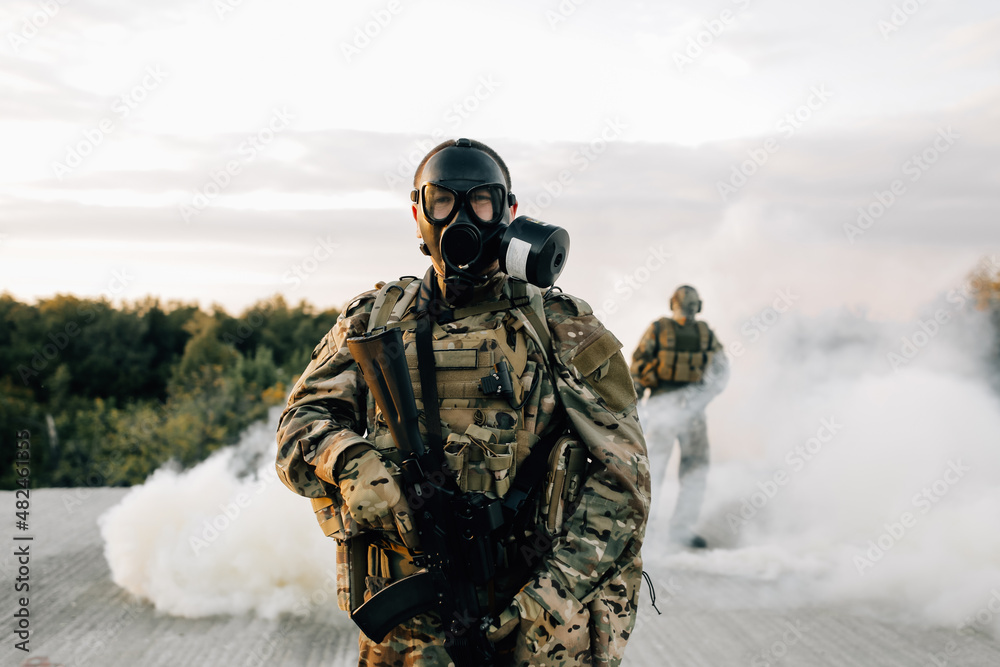 Military man in a gas mask shrouded in a smoke screen, standing with a ...