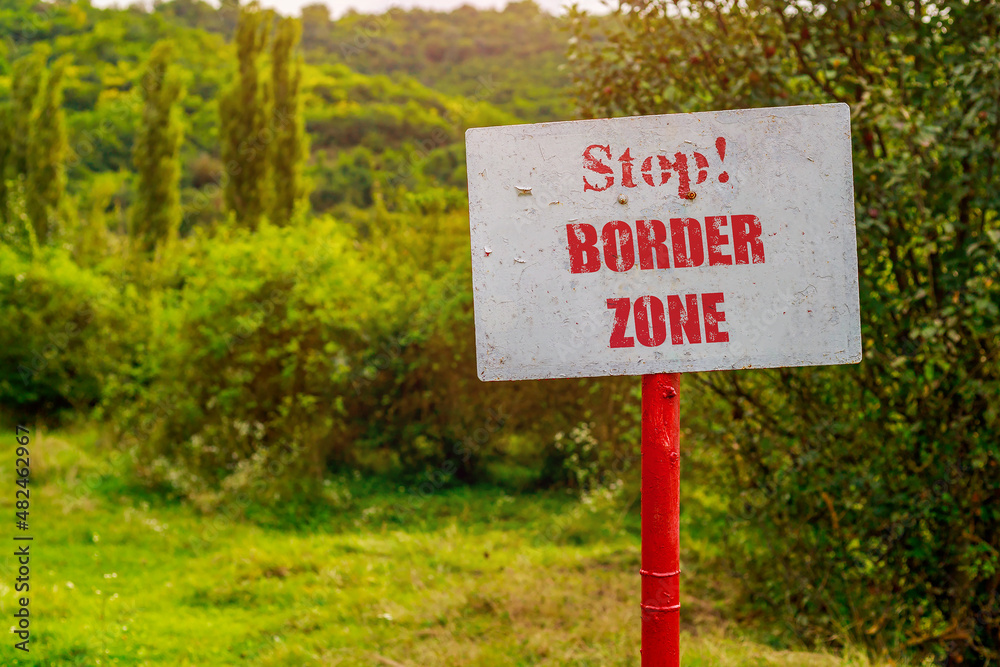 Inscription or text in English STOP BORDER ZONE. Warning post about the ...