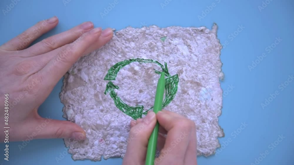 Women's hands draw a sign of reuse with a green felt-tip pen. Drawing ...