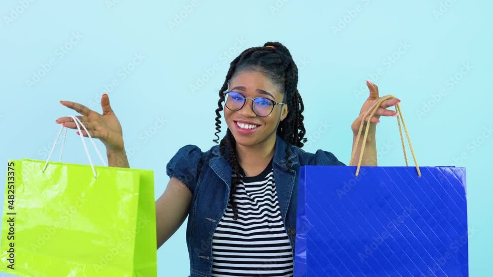 Cheerful young african american girl in blue clothes holding laminated ...